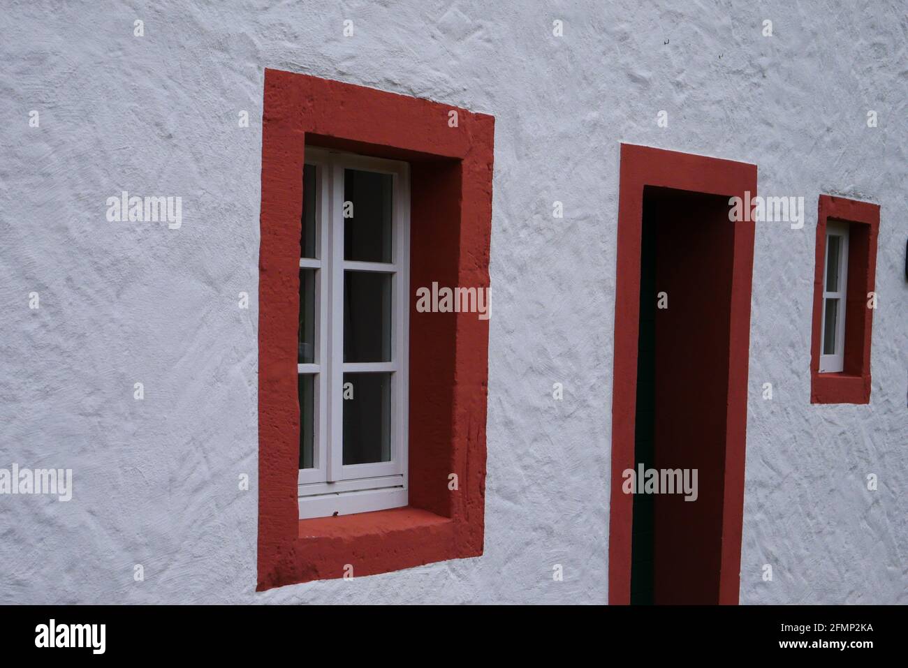 close up of a white house facade with white wooden windows and a red ...