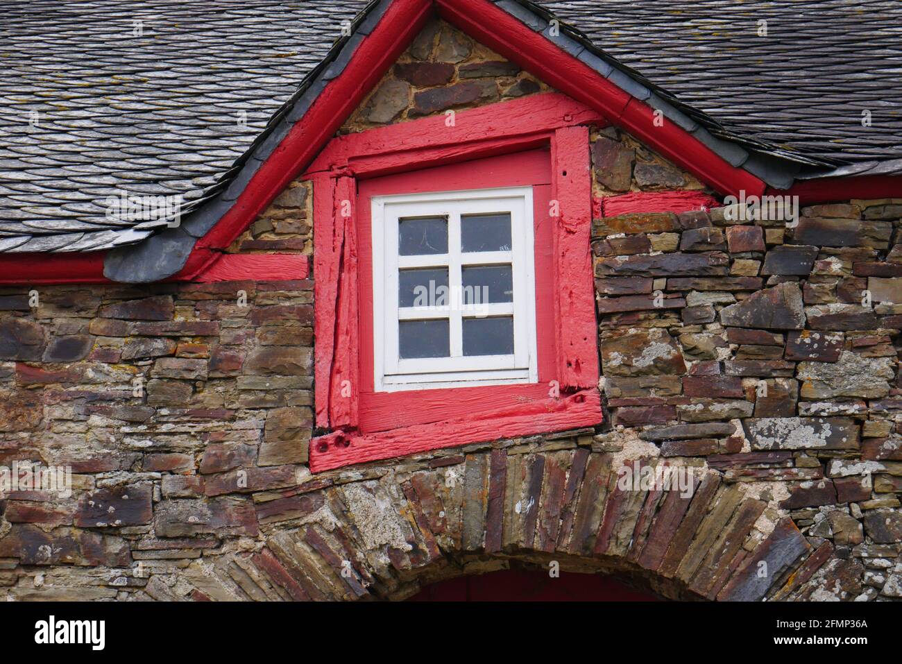 white window in a crooked red wooden frame of an old stone house from ...