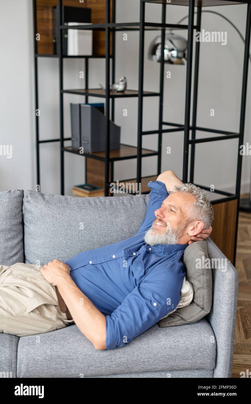 Vertical portrait of calm and tranquil senior bearded guy lying down on ...