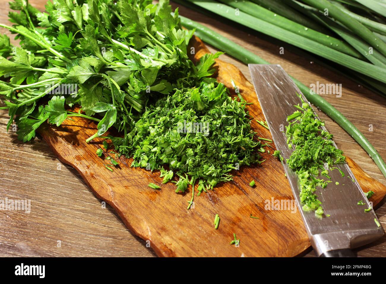 Cooking in the kitchen. Greenery. Green onions. Knife and cutting board ...
