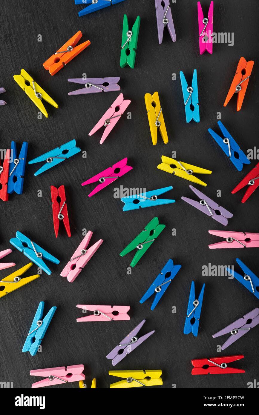 Clothespins of different colors in chaotic manner on black background ...