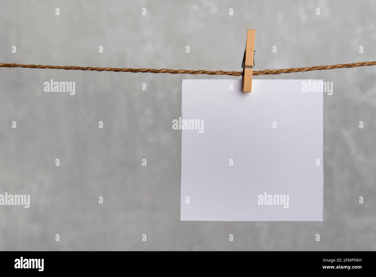 One blank square note paper card hanging with wooden clip on rope ...