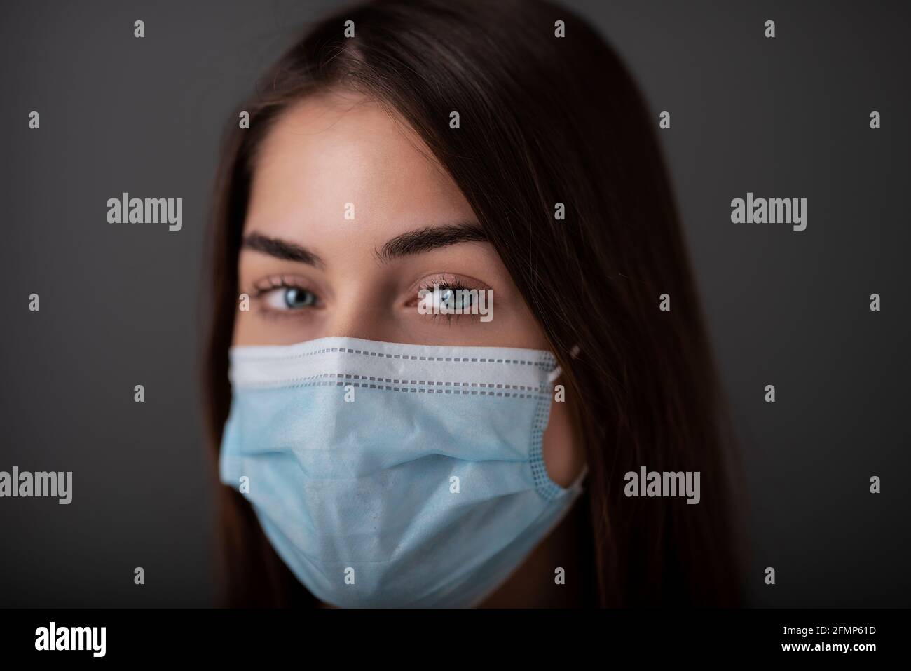 Studio portrait of young woman wearing face mask while standing at ...