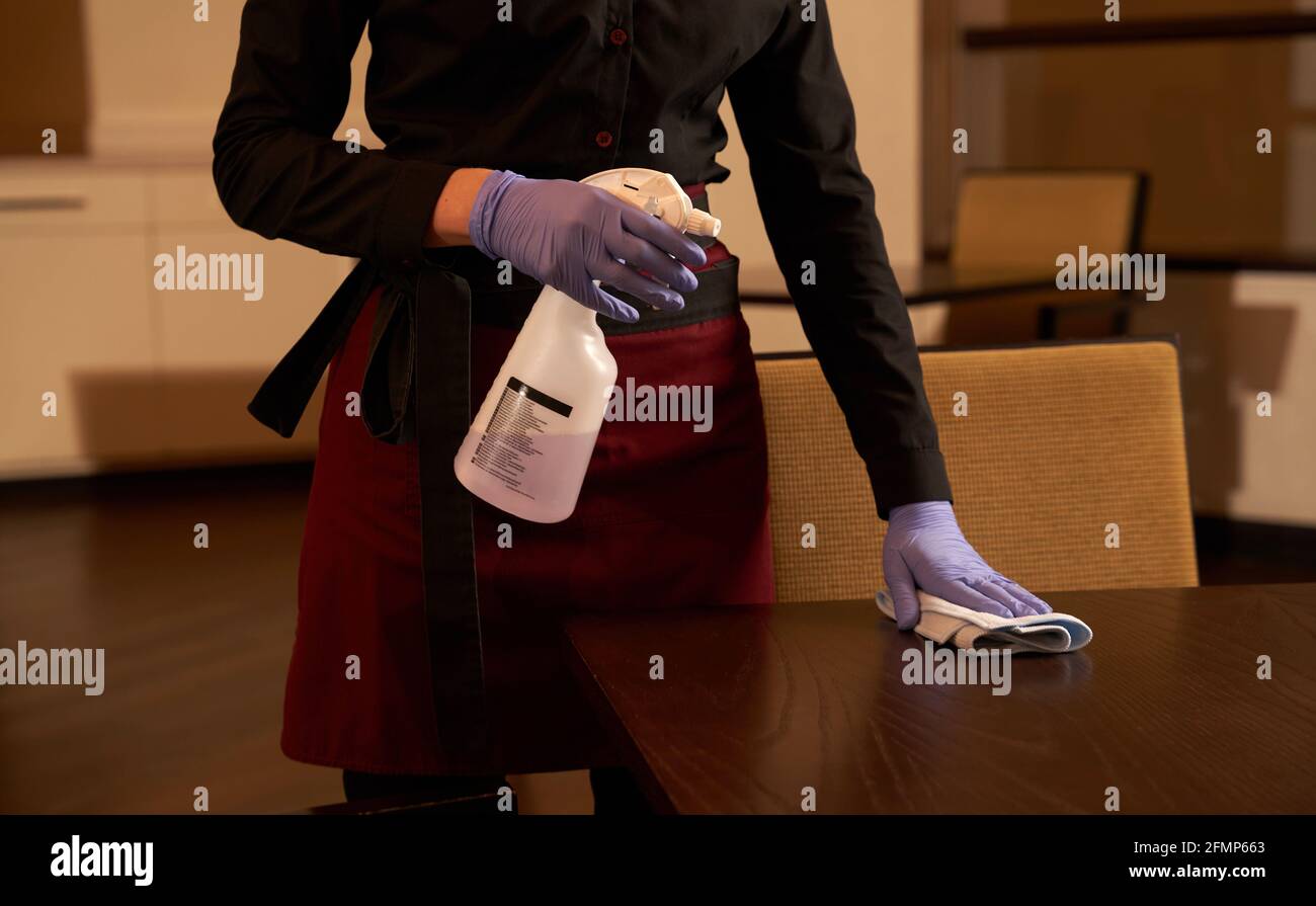 Waitress is cleaning table with disinfectant spray Stock Photo - Alamy