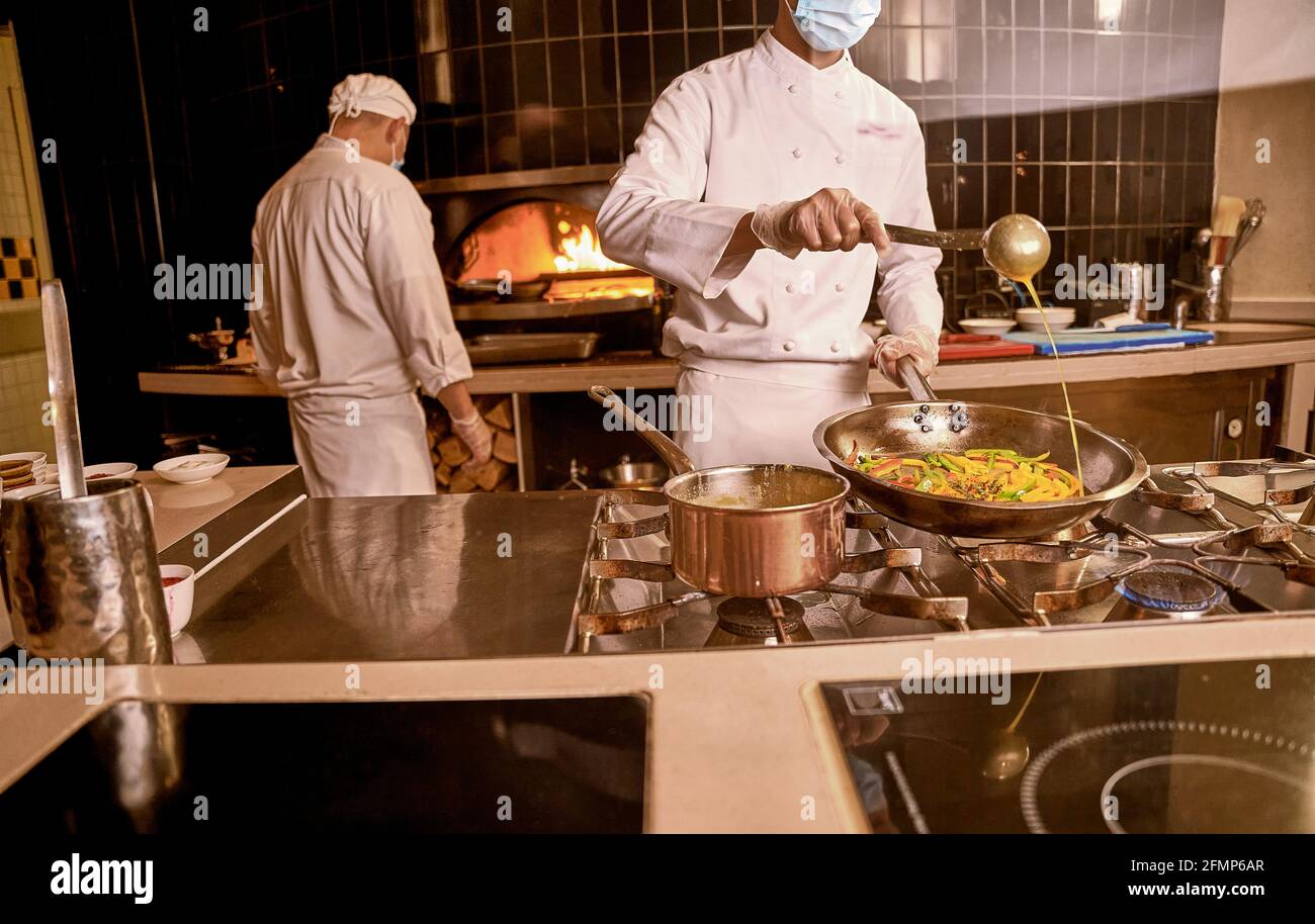 Chef adding sauce to vegetables in cooking pan Stock Photo - Alamy