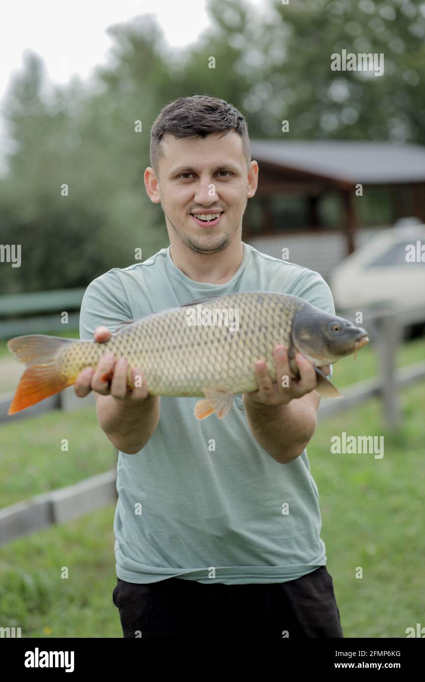 Happy angler holds trophy carp. Man with carp fish. Outdoors activities ...