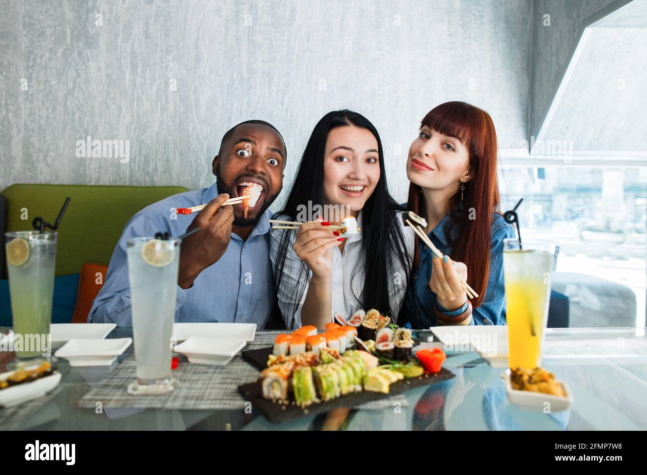 Sushi concept, seafood, asian meal. Three young multiethnic friends ...