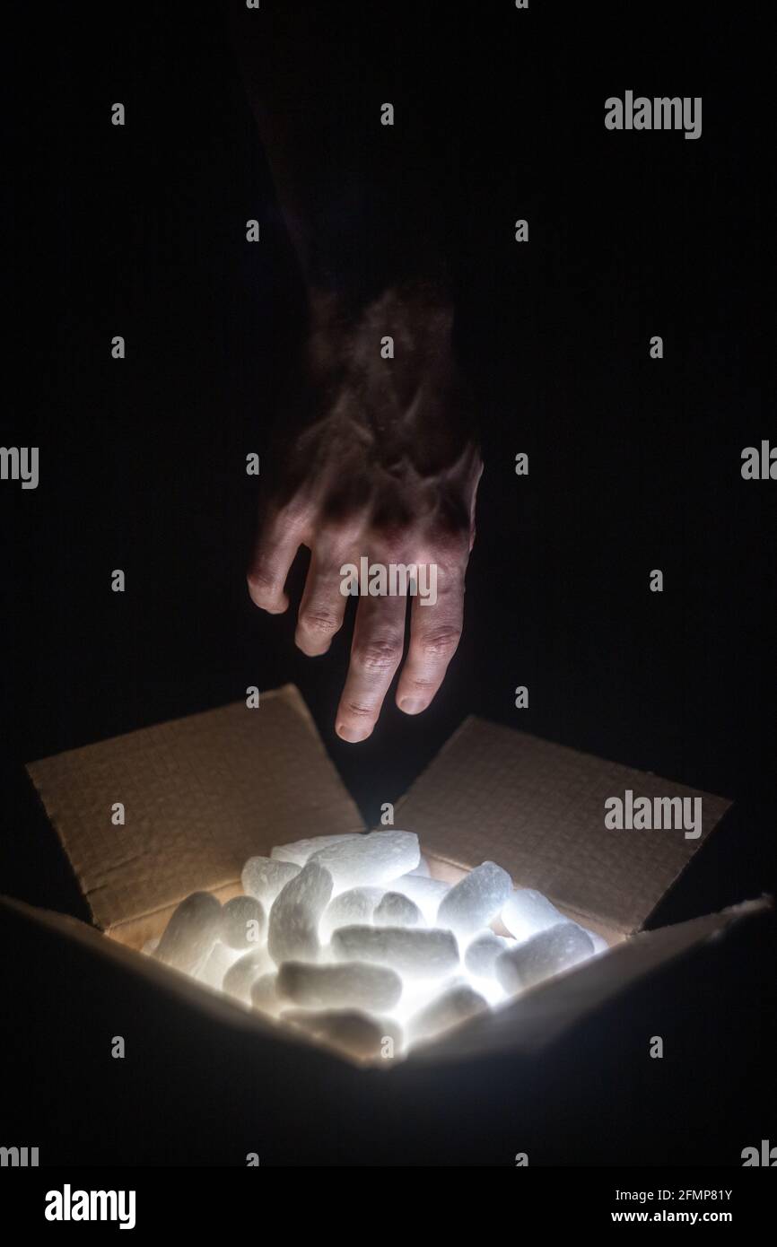 Mysterious glowing package with hand reaching in Stock Photo - Alamy