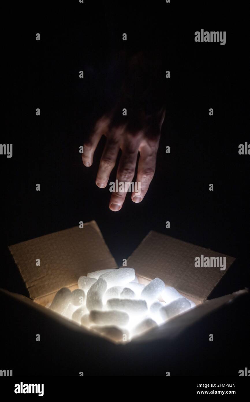 Mysterious glowing package with hand reaching in Stock Photo - Alamy