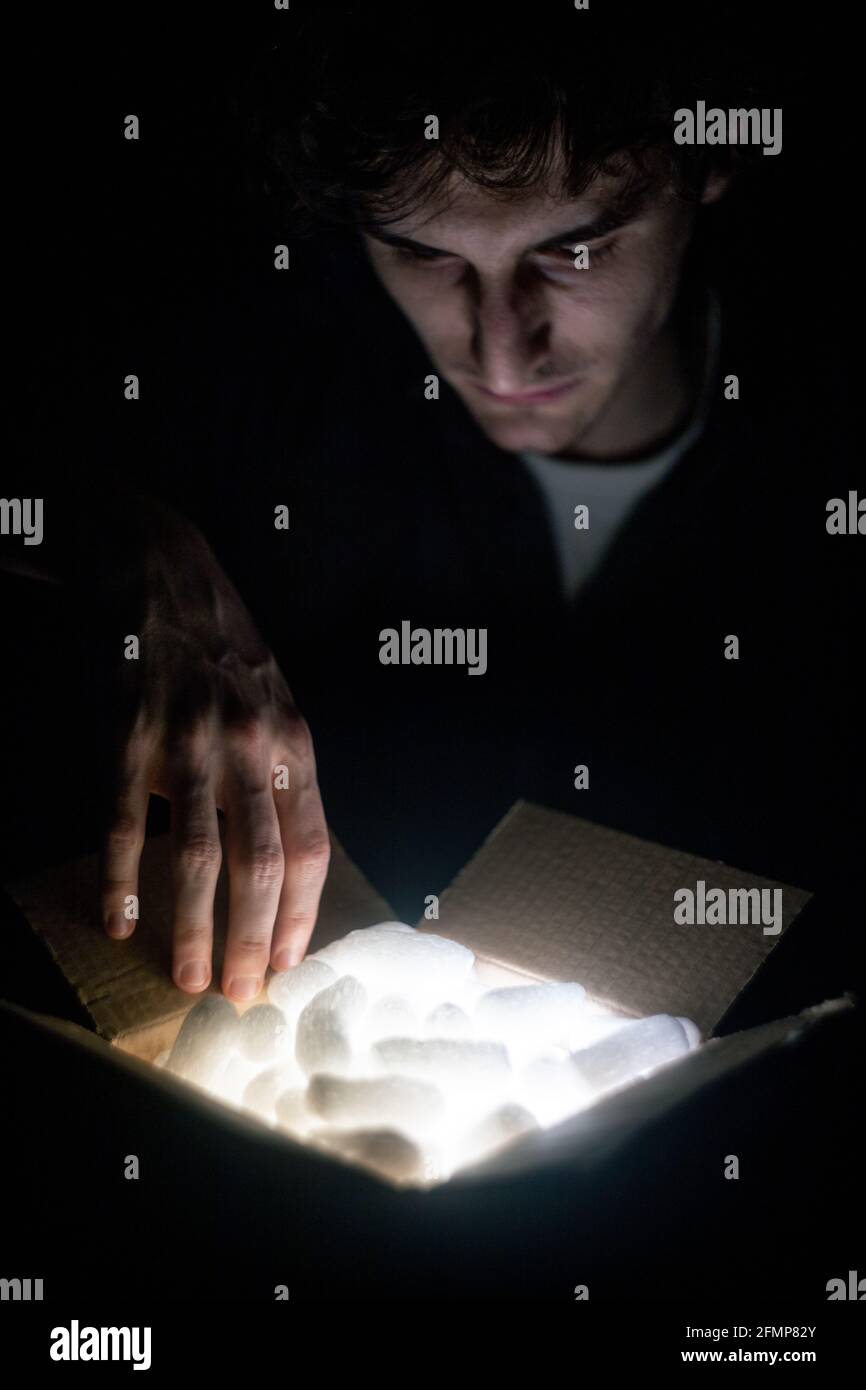 Mysterious glowing package with hand reaching in Stock Photo - Alamy