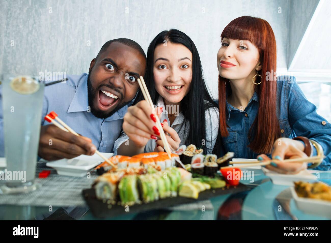 People, food and friendship concept. Three happy young friends enjoying ...