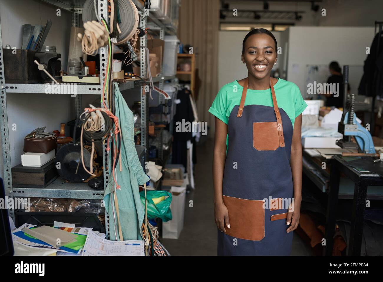 Smiling young African female leather worker standing in her shop Stock ...