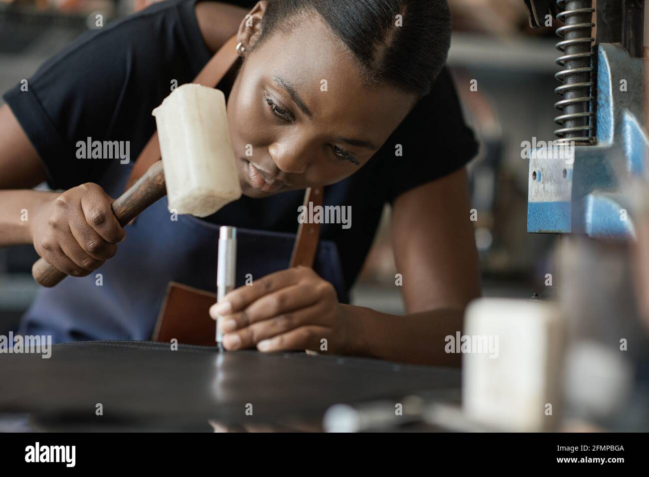 African female artisan using a mallet and punch in her studio Stock ...
