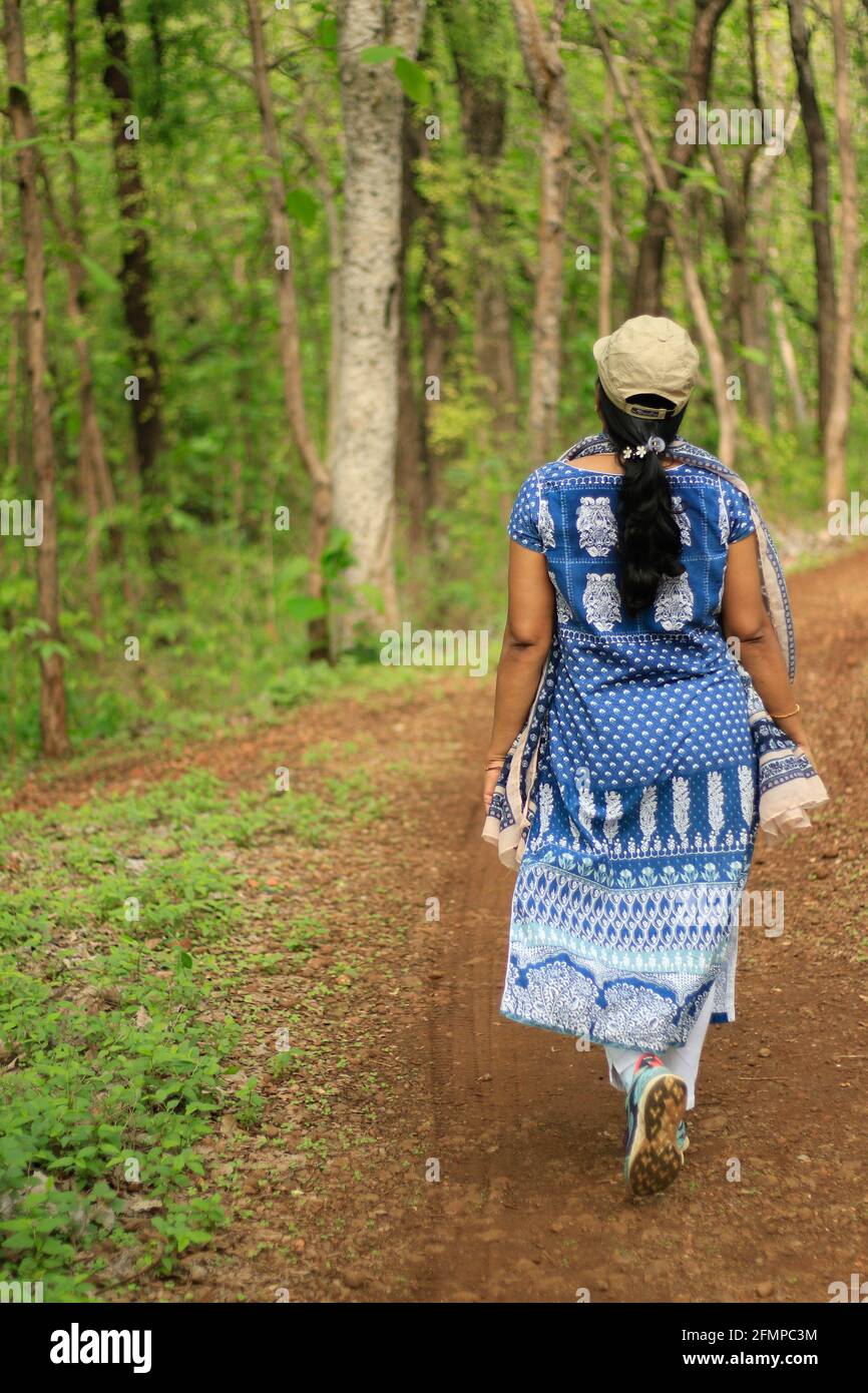 Backside view of a middle aged (40-45 yr old) woman walking in a forest ...