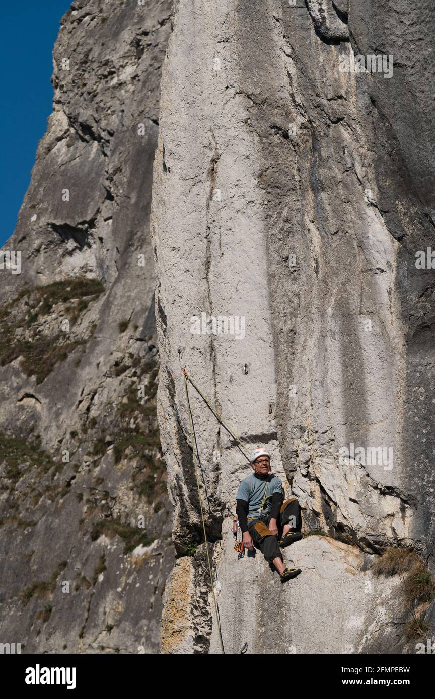 Tired climber rests in the middle of the climbing wall Stock Photo - Alamy