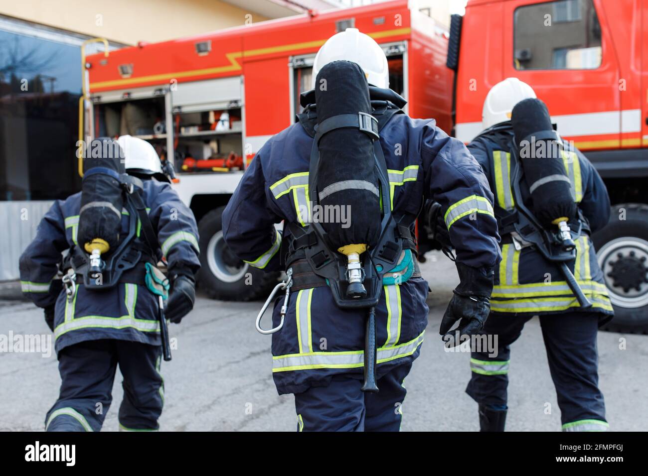 Portrait of firefighter in uniform in front of fire engine machine and ...