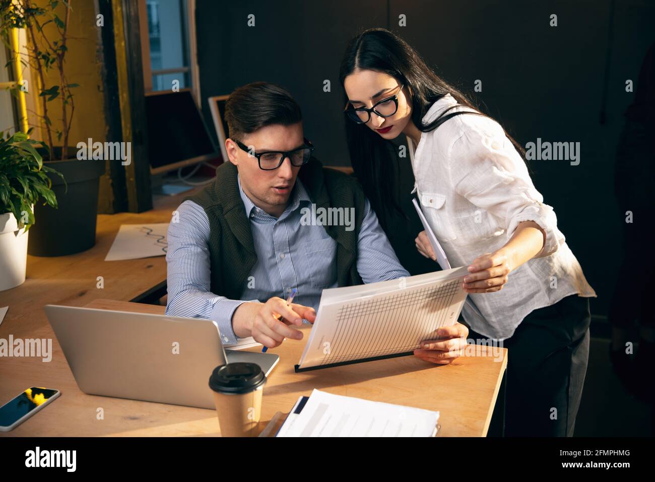 Colleagues working together in modern office using devices and gadgets ...