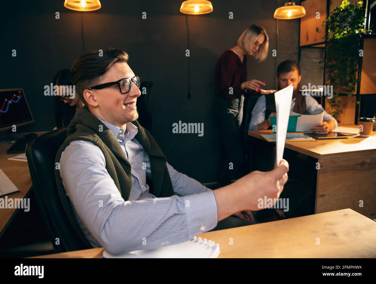 Colleagues working together in modern office using devices and gadgets ...