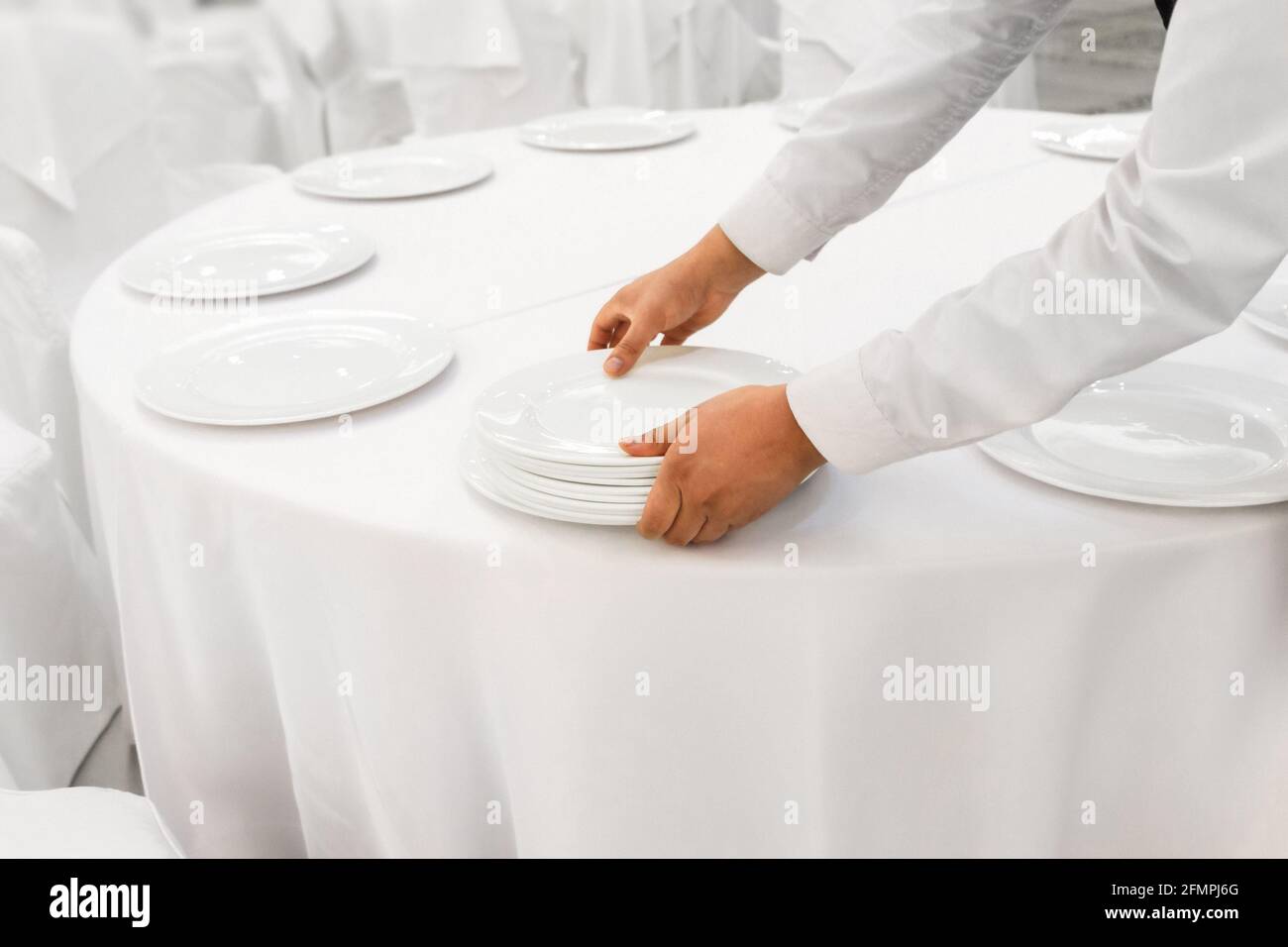 Close-up waiter man hands serving white banquet table at restaurant ...
