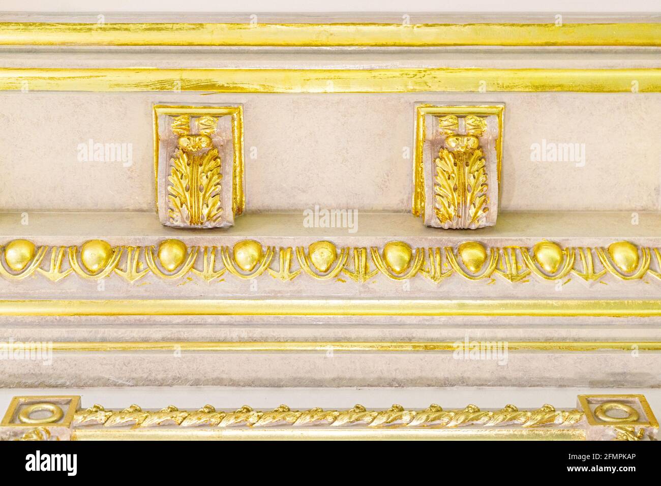 Close-up decorative gold stucco on the ceiling fillet in luxurious ...