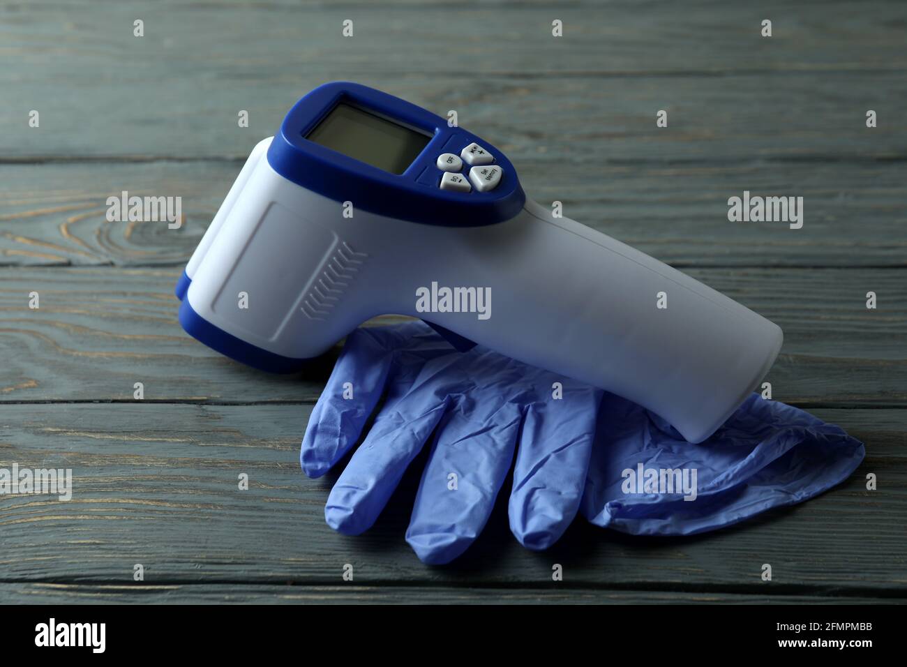 Medical glove and thermometer gun on wooden background Stock Photo - Alamy