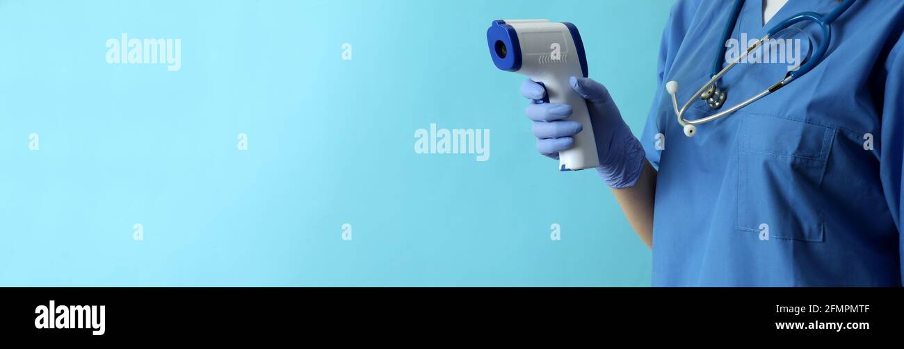 Female doctor hold thermometer gun on blue background Stock Photo - Alamy