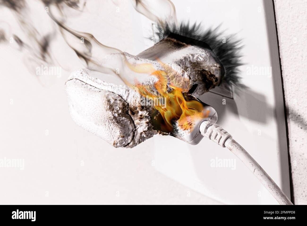 cell phone charger on fire, short circuit in outlet Stock Photo - Alamy