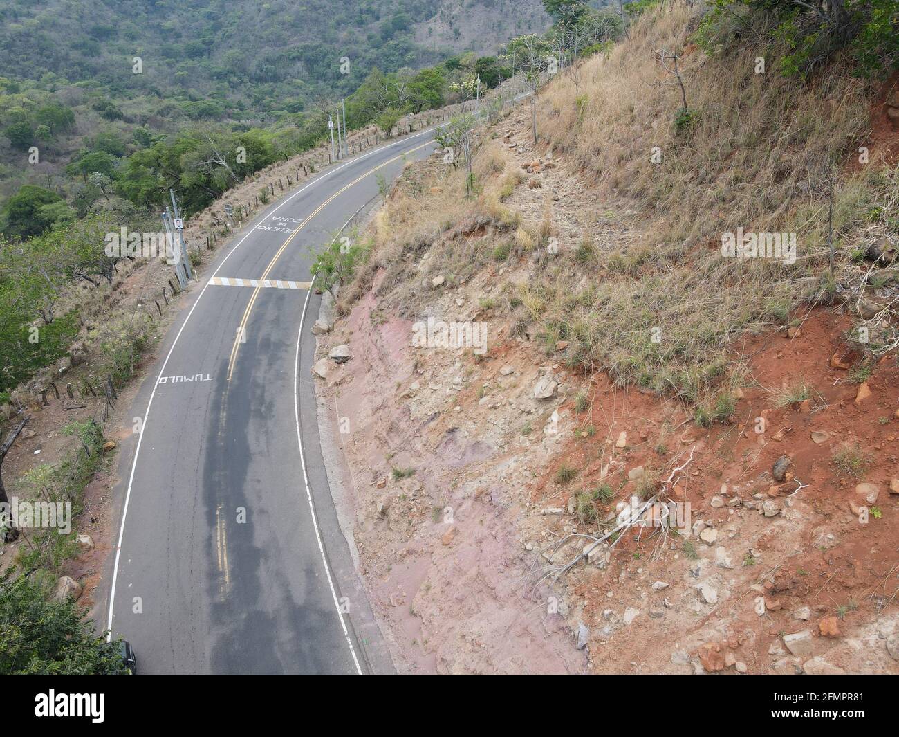 View of the curve of a road at the foot of a mountain Stock Photo - Alamy