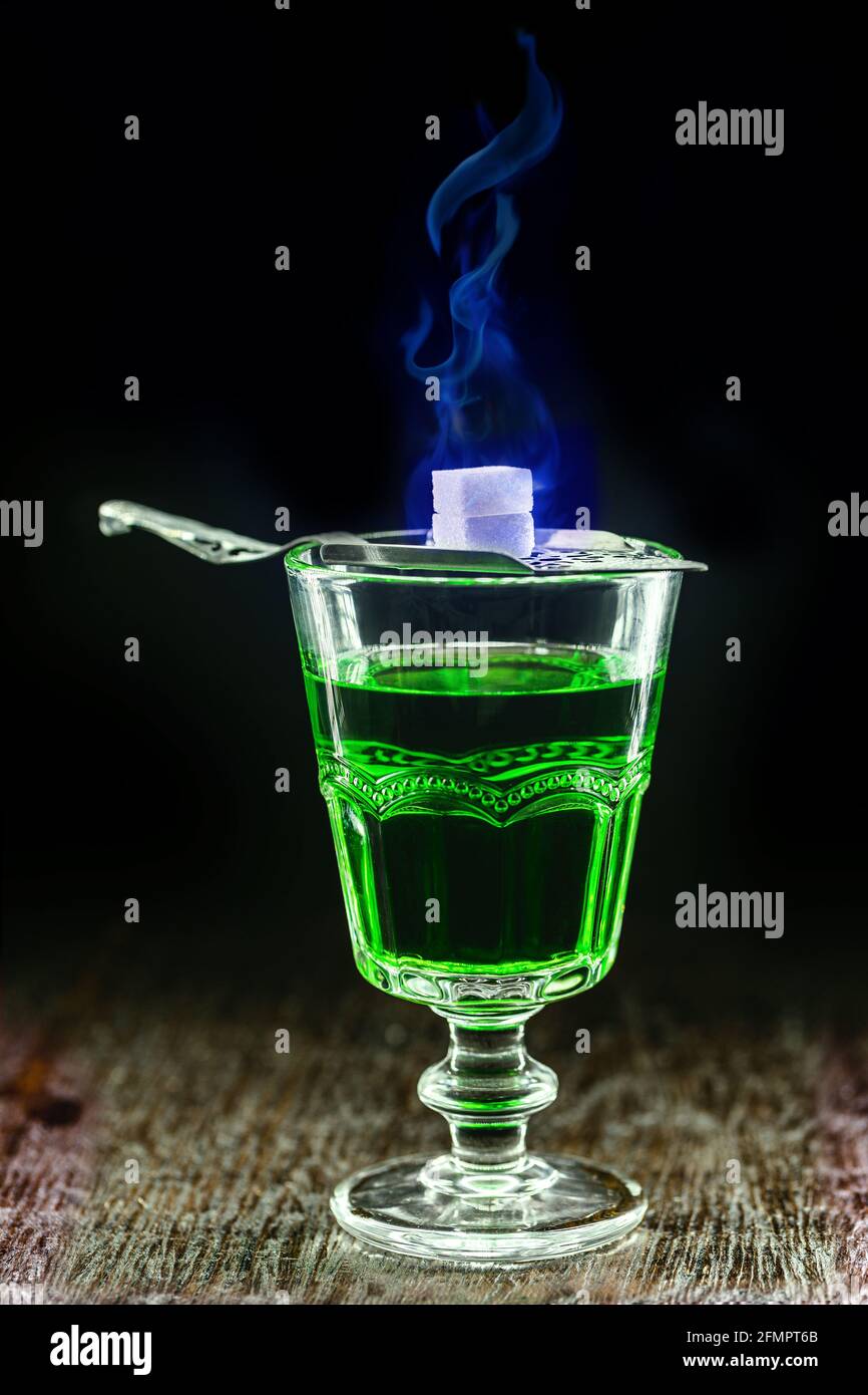 classic absinthe cup with metal spoon and sugar melting in blue flame ...