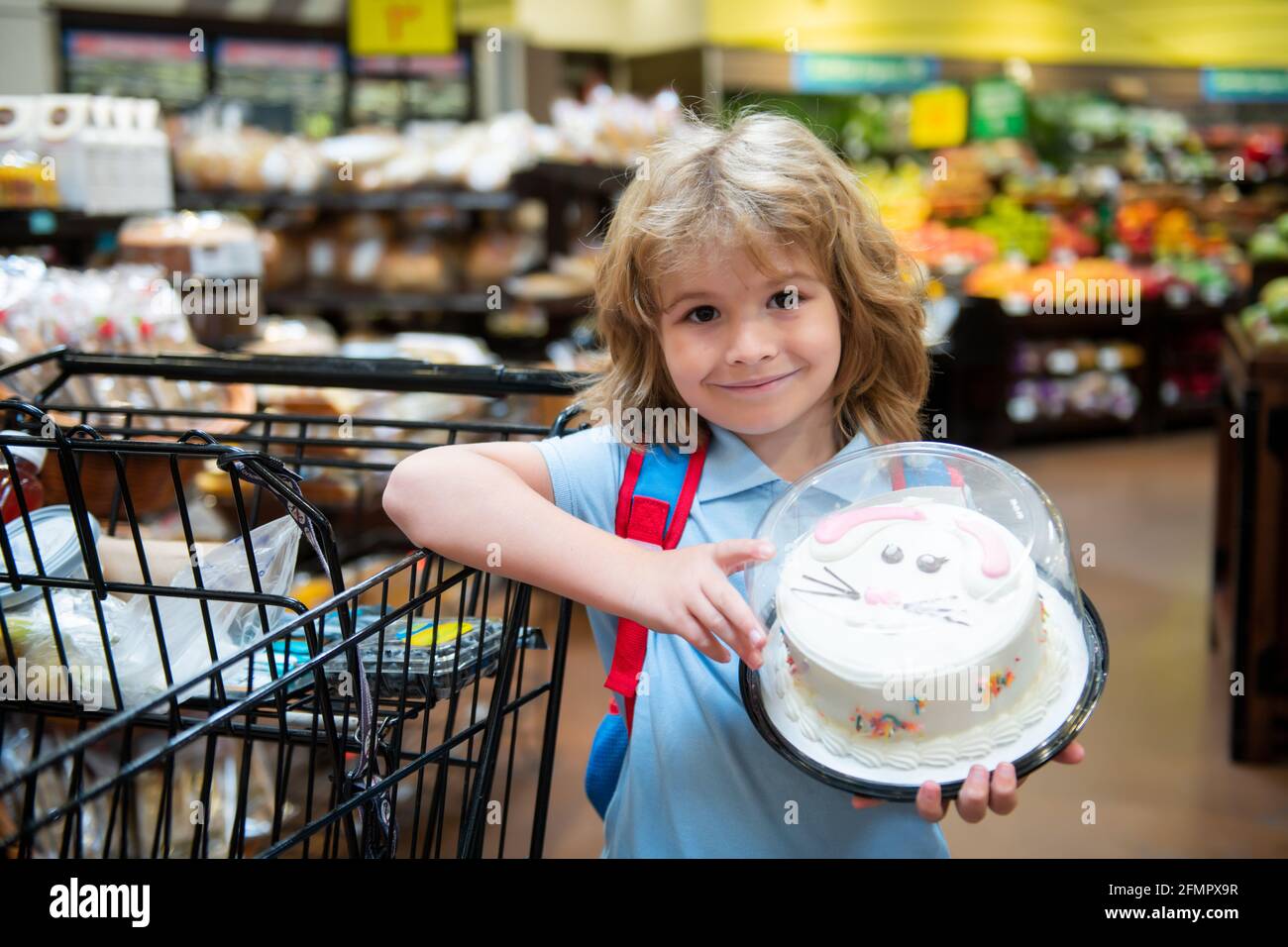 Child with shopping basket purchasing cake in a grocery store ...