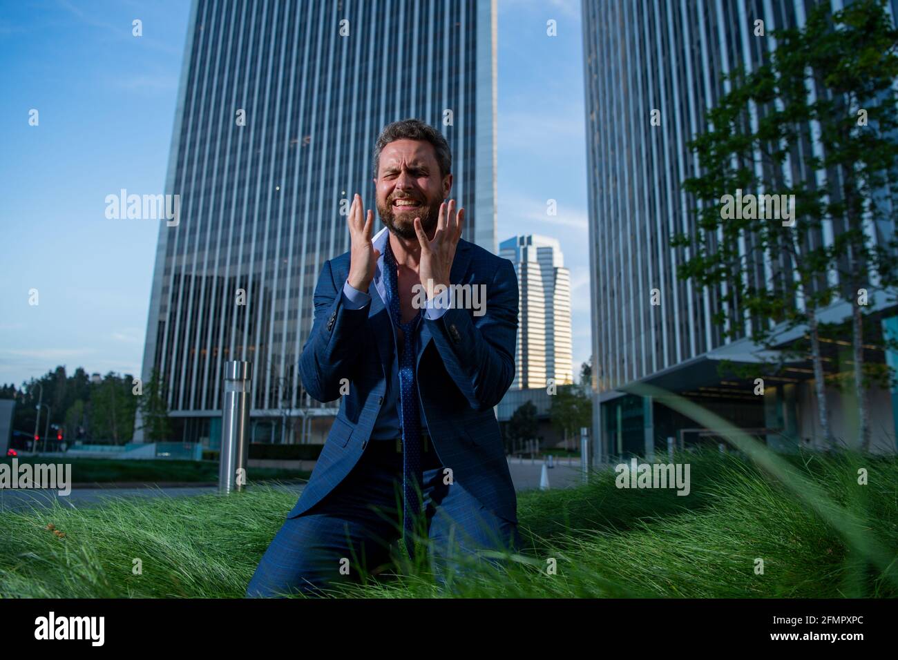 Business man crying in depression sitting on ground grass street ...
