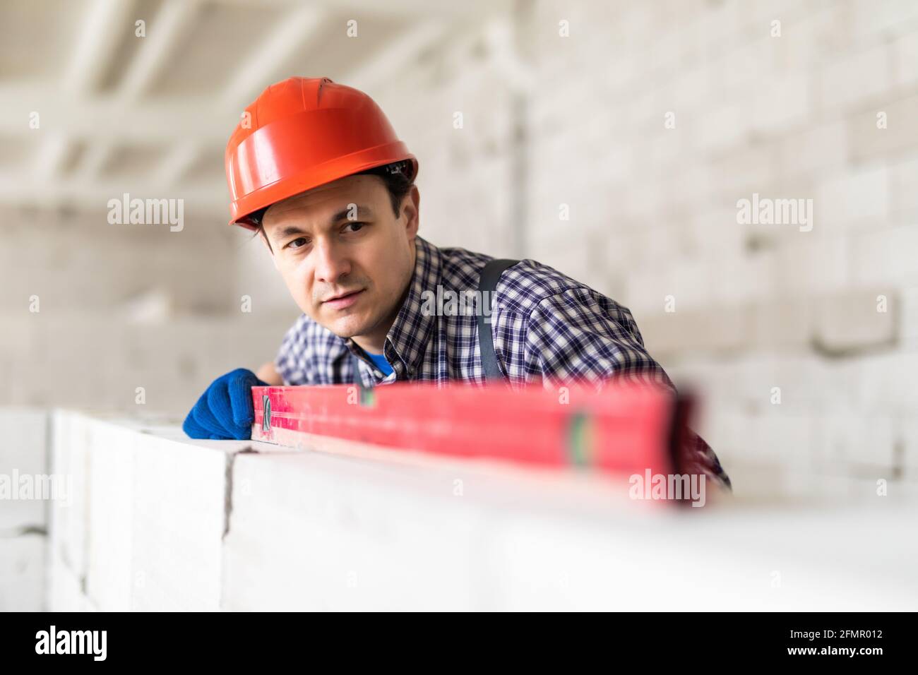Construction worker observing and surveying wall alignment using water ...