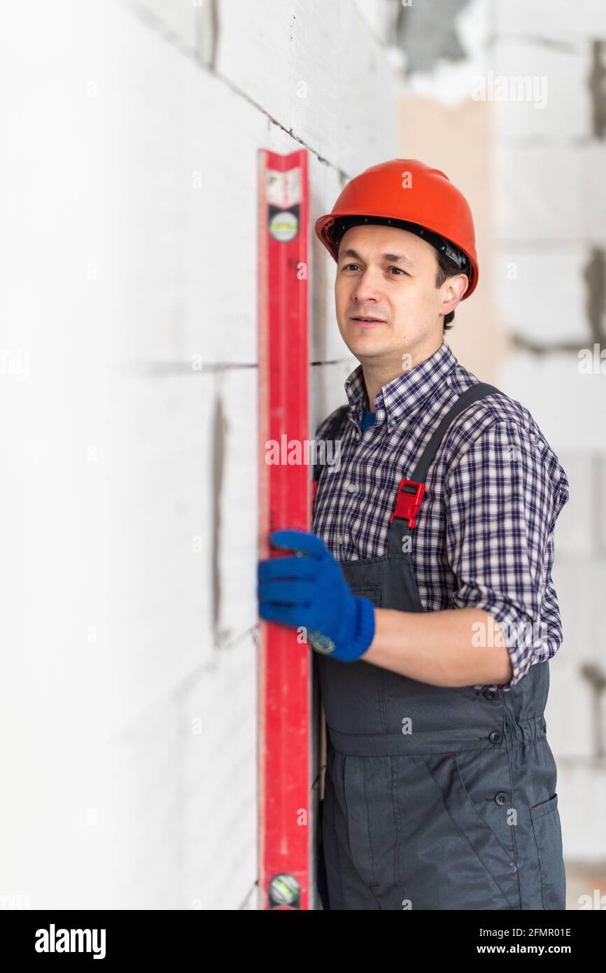 Construction worker observing and surveying wall alignment using water ...