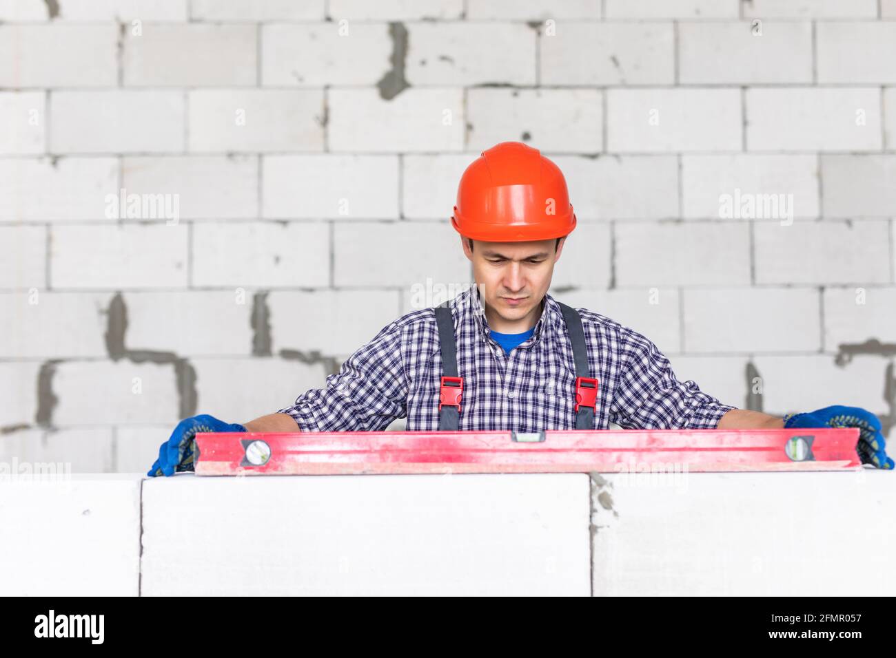 Construction worker observing and surveying wall alignment using water ...