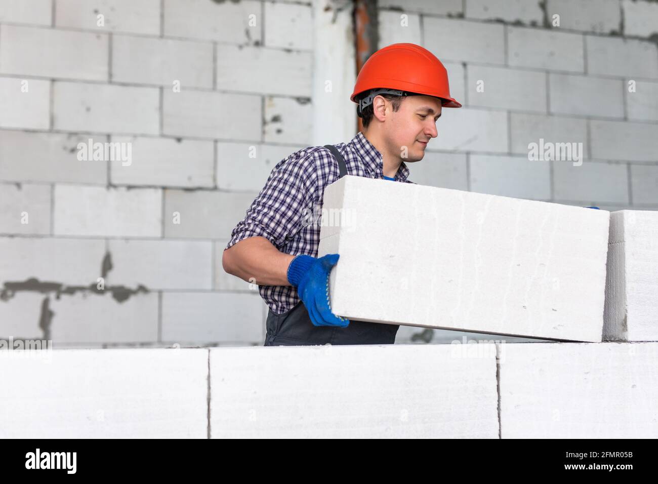 Man aligning aerated autoclaved concrete block of constructed house ...