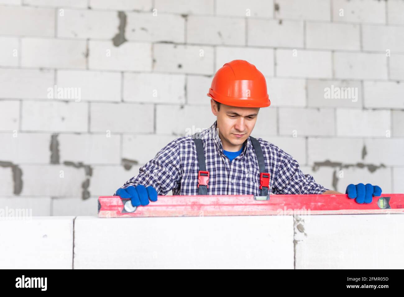 Building worker measuring the wall with a water level at construction ...