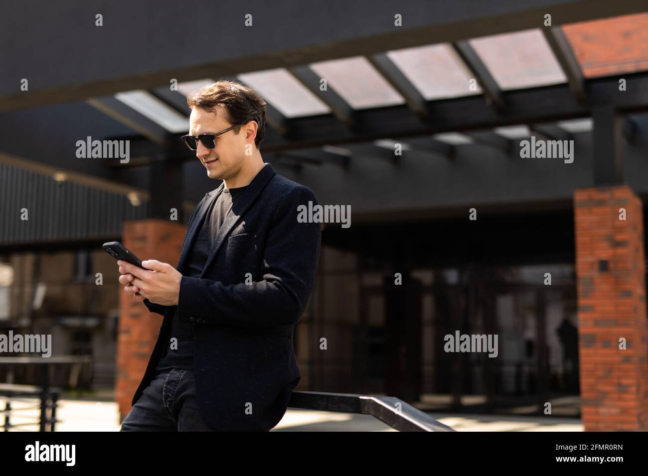 Portrait cheerful businessman using phone at modern street. Joyful ...