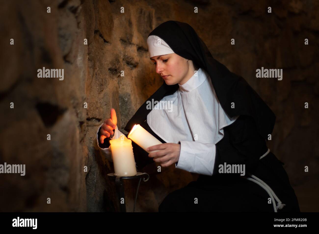 Young nun reverently lights a candle Stock Photo - Alamy