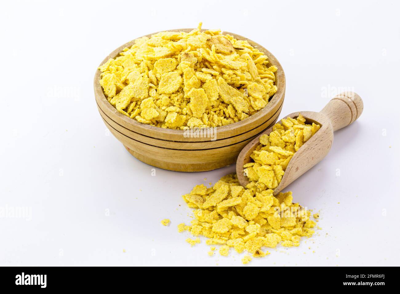 toasted cornmeal flakes in wooden measuring spoon, isolated white ...
