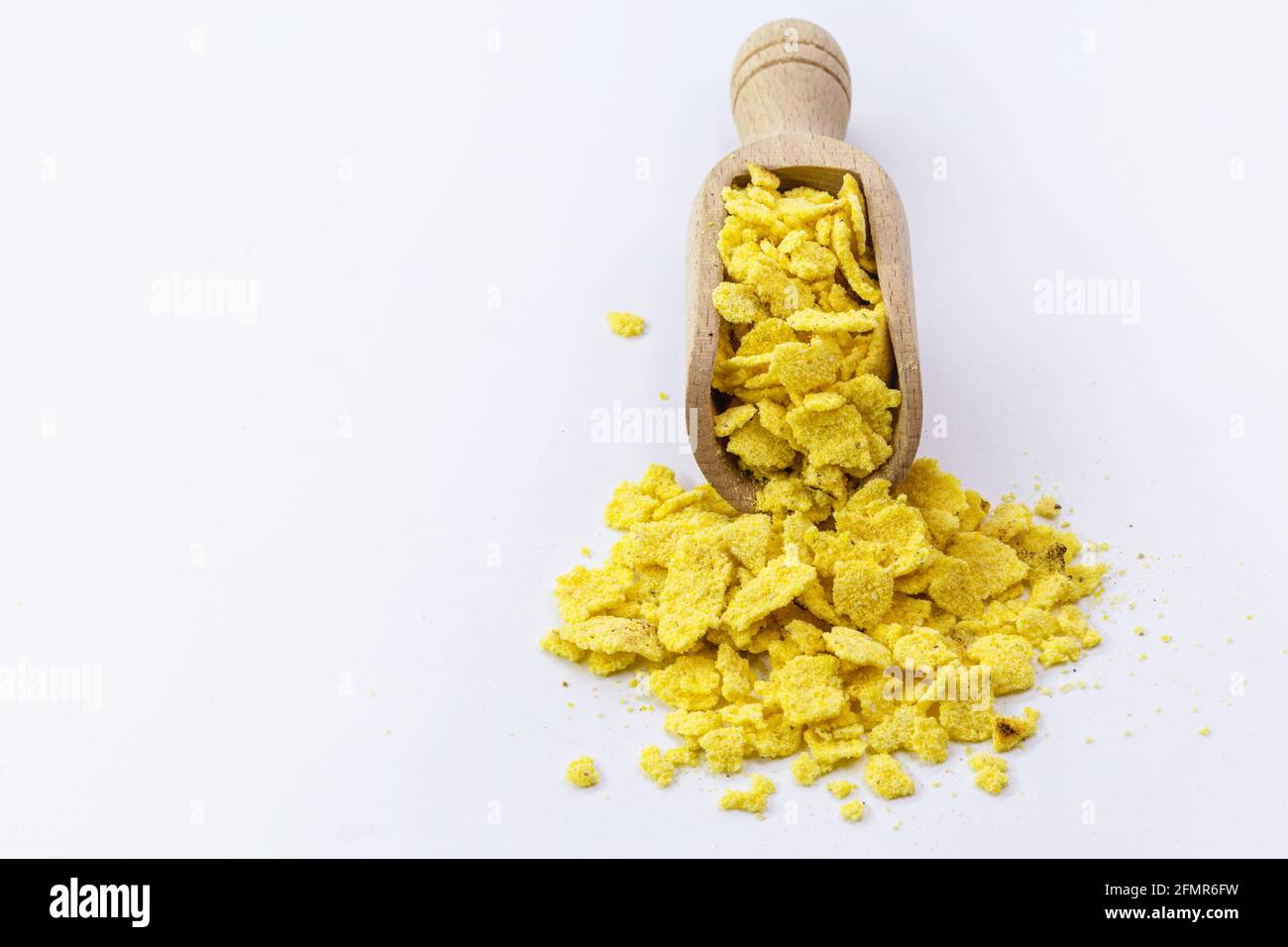 toasted cornmeal flakes in wooden measuring spoon, isolated white ...
