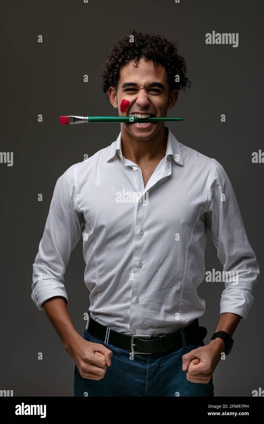Successful playful confident young artist with daub of red paint on his ...