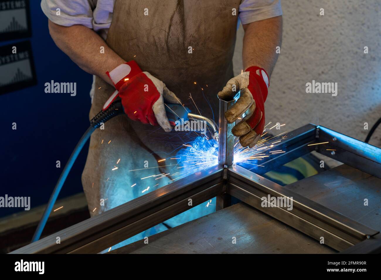 Detail of a man welding steel frames in a forgery and metal works ...