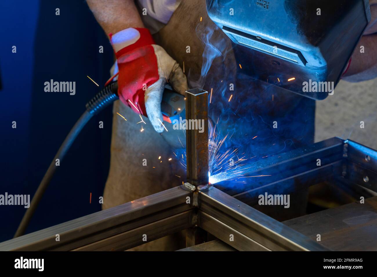 Detail of a man welding steel frames in a forgery and metal works ...