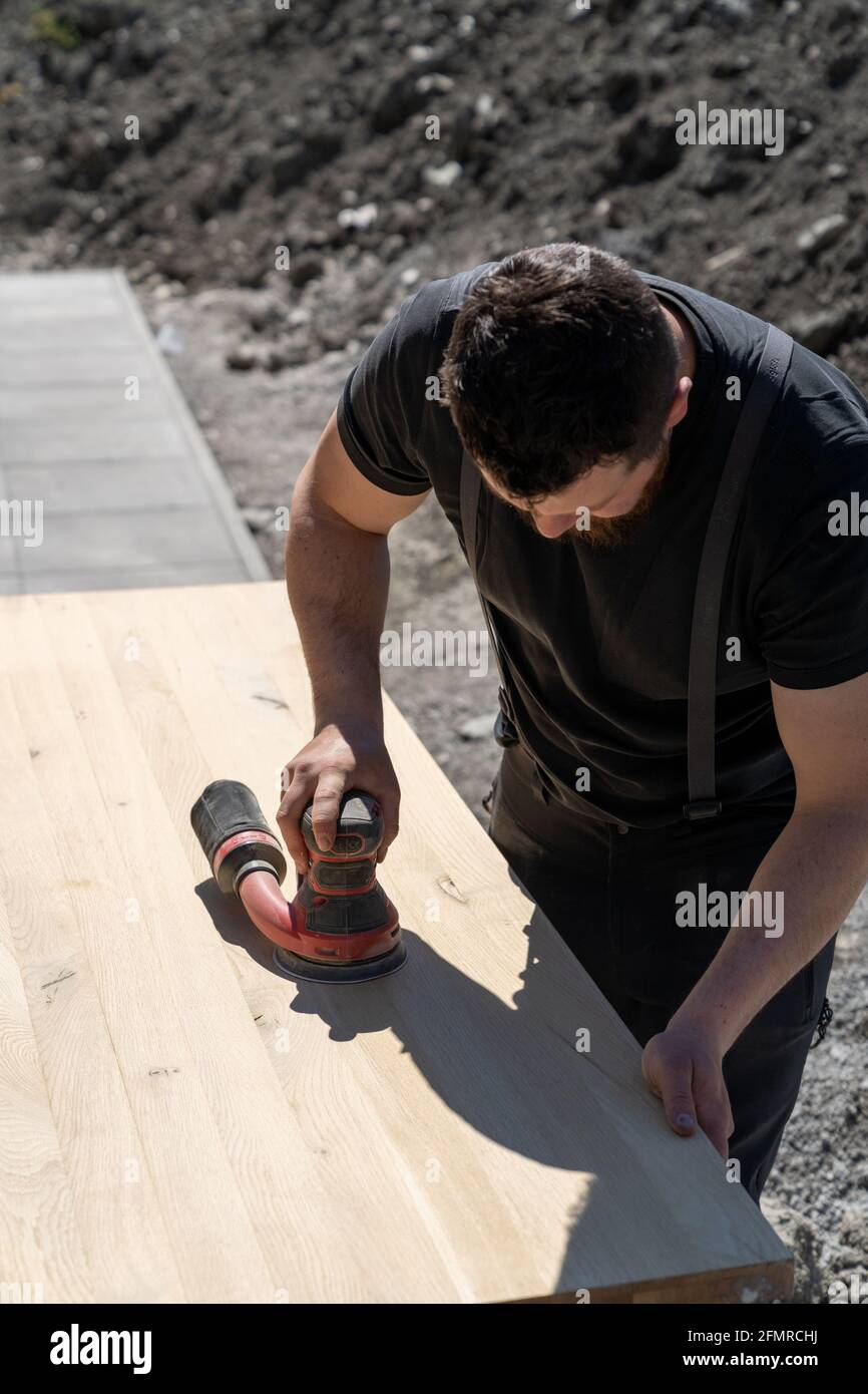 A construction worker using a cordless power sander to sand a massive ...