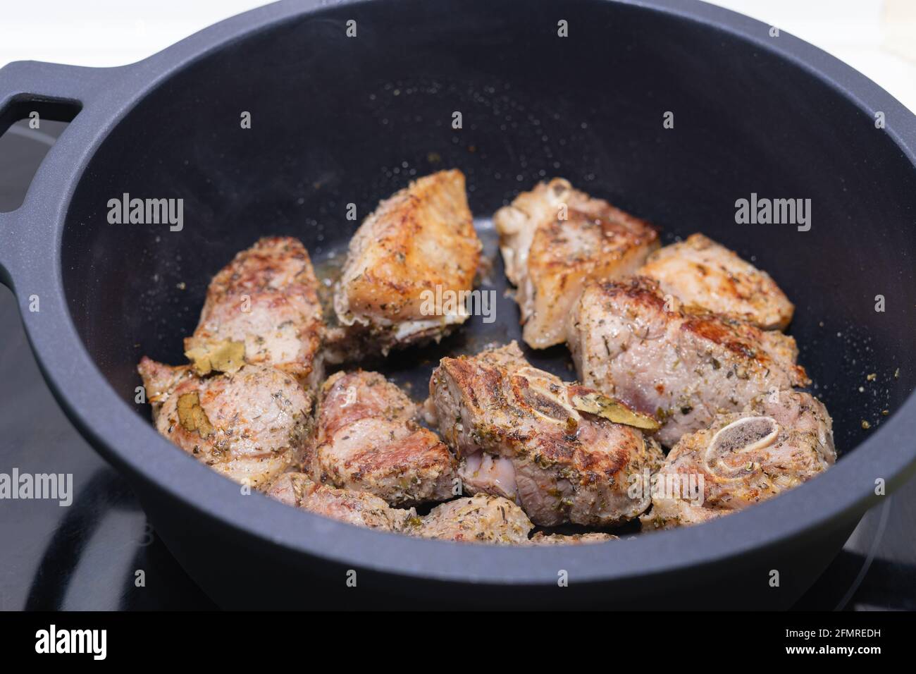 Meat being cooked in a black pot. Cooking concept Stock Photo - Alamy