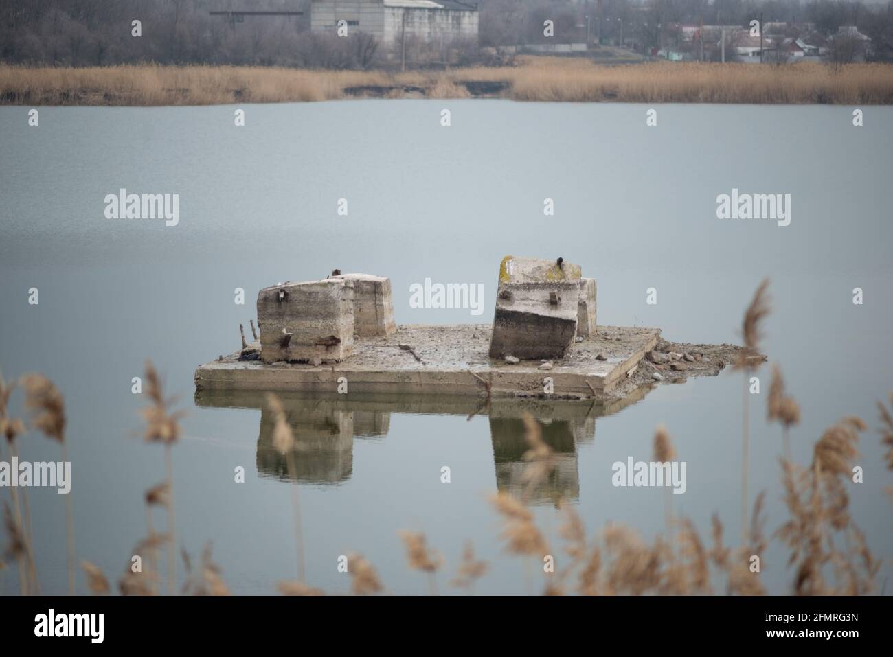 old concrete structure on the water of a drying lake, against the ...