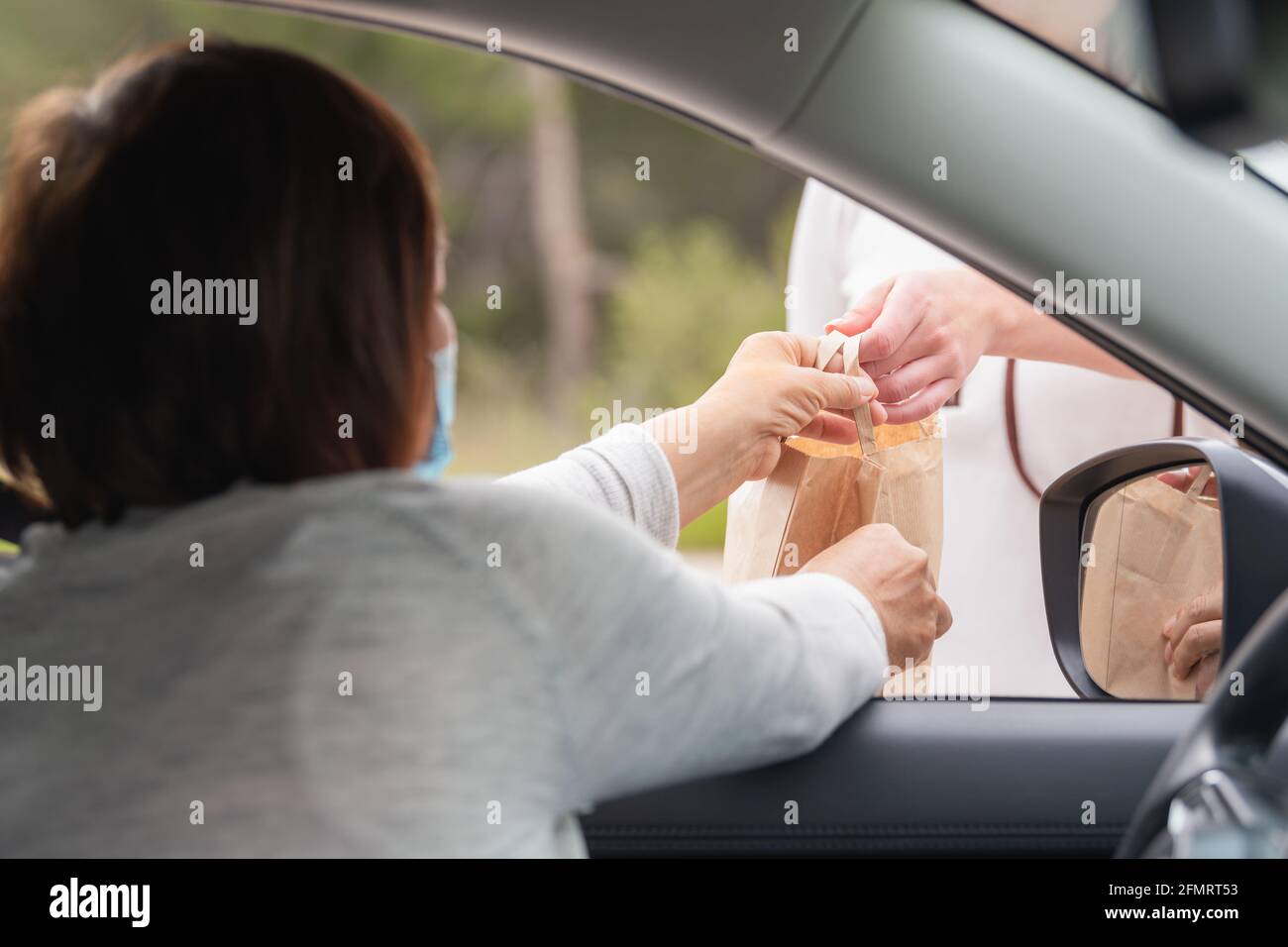Woman in a car grabbing a paper bag from another woman Stock Photo - Alamy