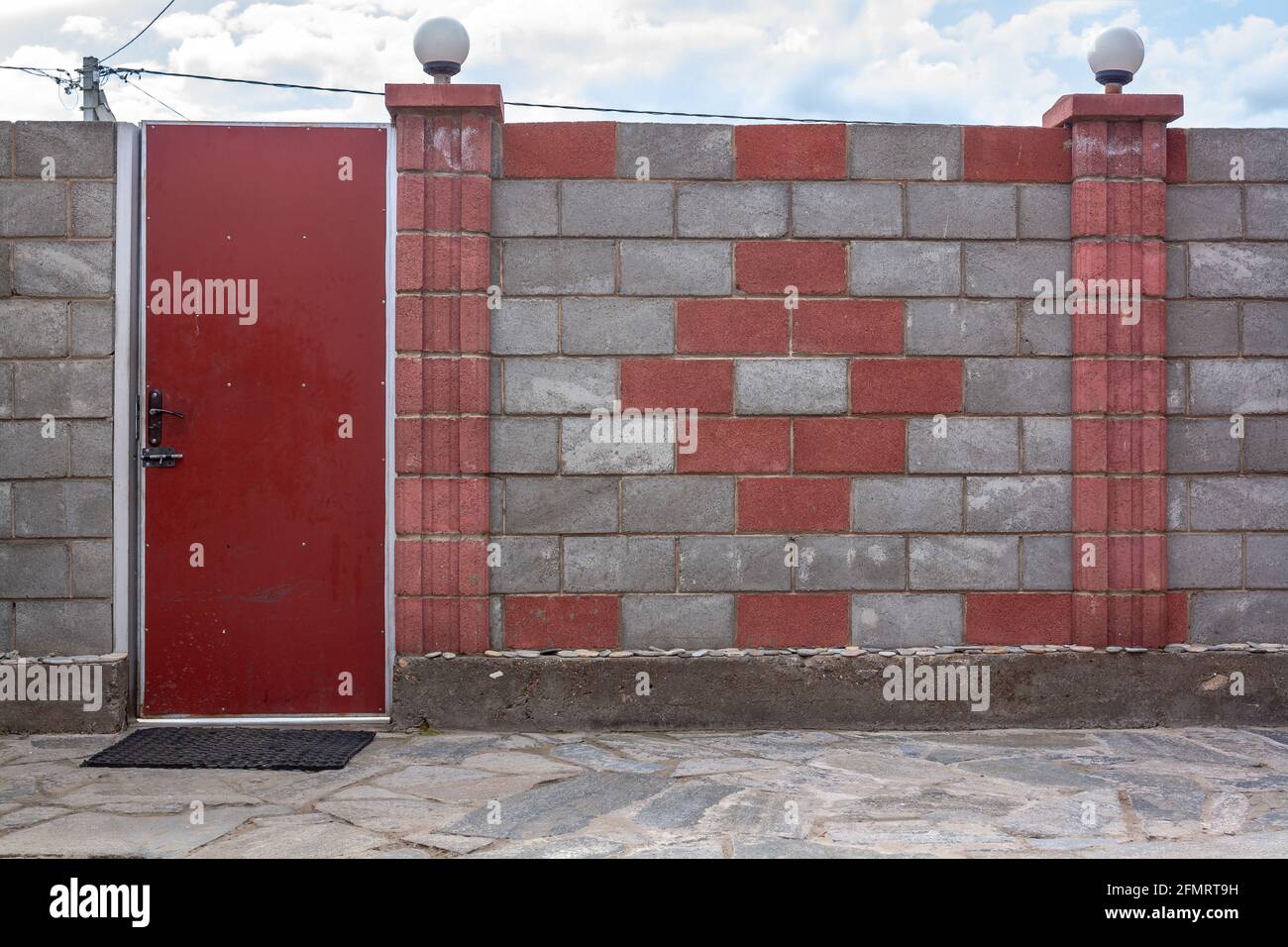 Fence made of blocks lined with pattern with pillars and iron door ...