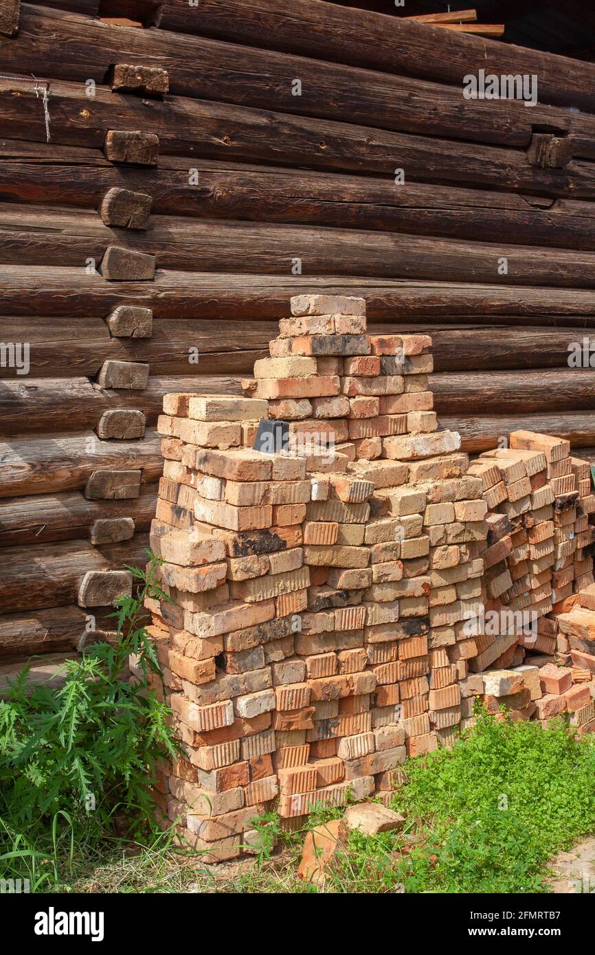 Old fireclay bricks are piled up against a log wall. Vertical image ...