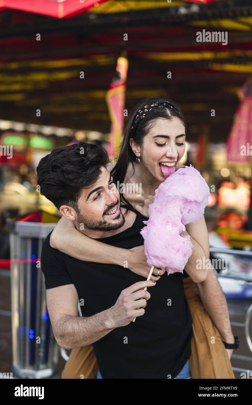 Young romantic couple eating cotton candy and having fun at an ...